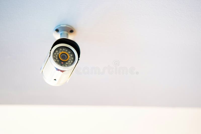 White CCTV with Orange Black Camera Len in the Centre Hanging from the ...
