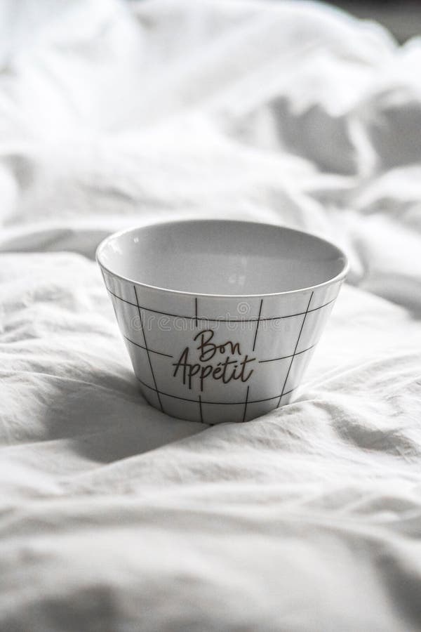 White Ceramic Bowl Sits Atop a White Sheet on a Bed. Stock Photo ...