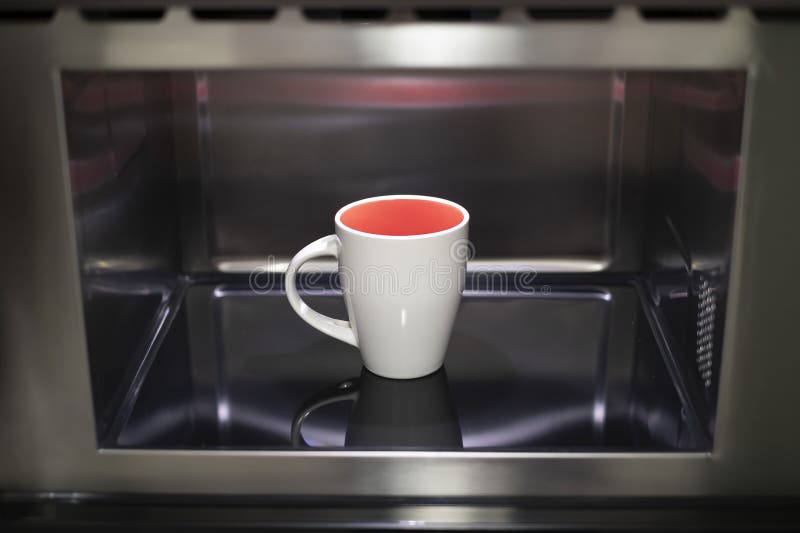 A White Ceramic Mug with a Red Interior Inside a Stainless Steel ...