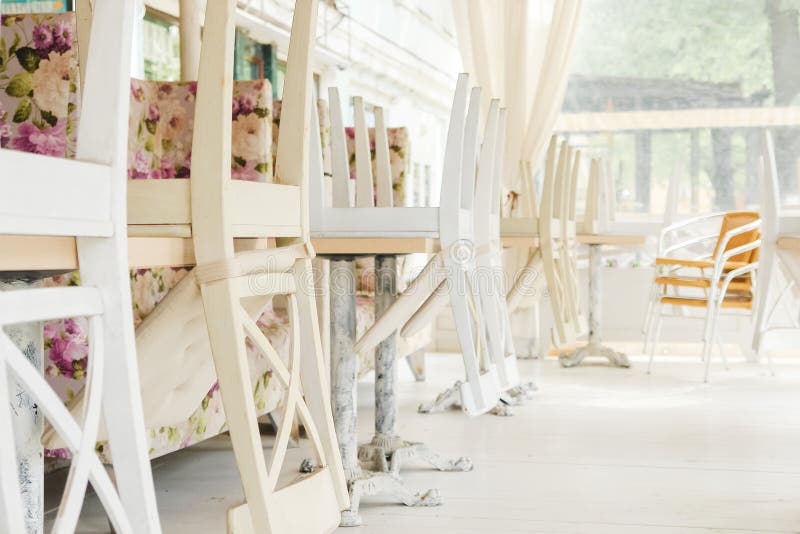 White Chairs on Tables Upside Down on Street Cafe Summer Terrace. Stock ...