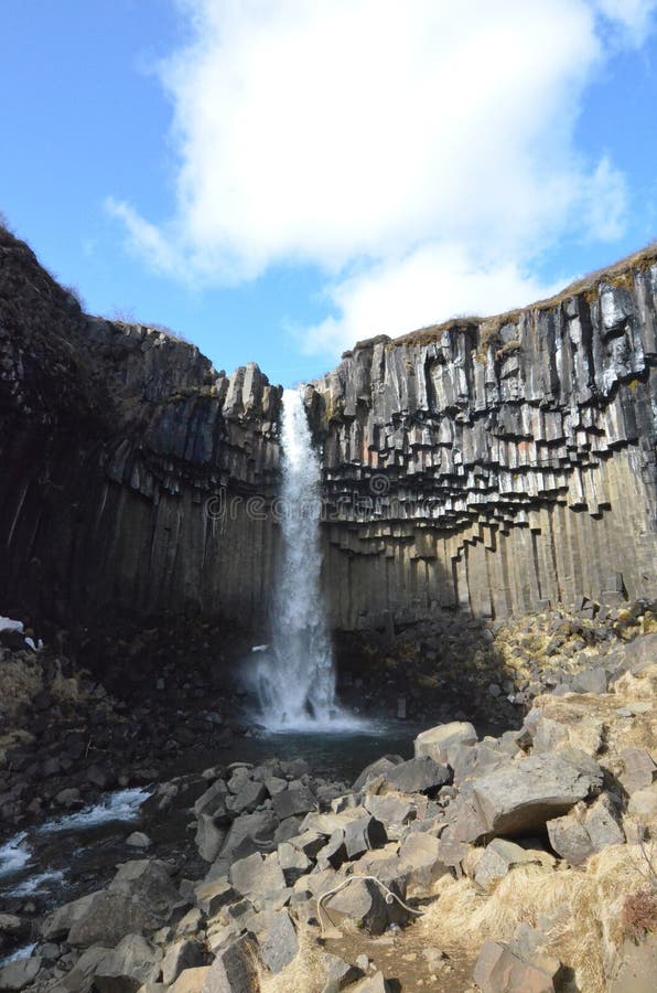 White Clouds Over a Basalt Column Waterfall Stock Photo - Image of ...