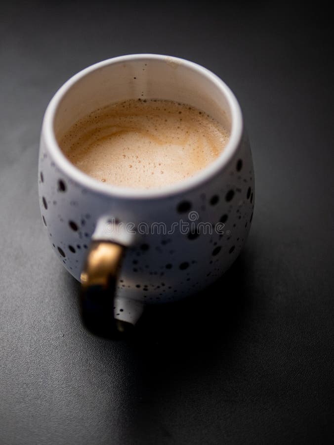 A White Coffee Mug with a Gold Handle and Black Spots Stock Image ...