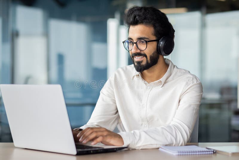 A White-collar Worker at a Desk Using a Laptop with Headphones. Stock ...
