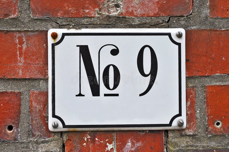 A White Colored House Number Plaque, Fixed on a Brick Wall, with the ...