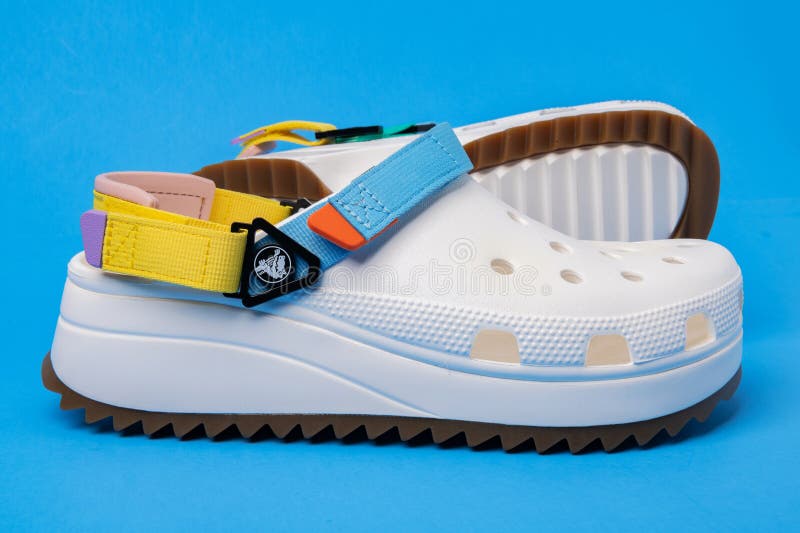 White Crocs Sandals with Colored Straps on a Blue Background Editorial ...