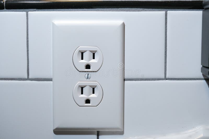 White Electrical Outlet with White Cover on a White Subway Tile Wall ...