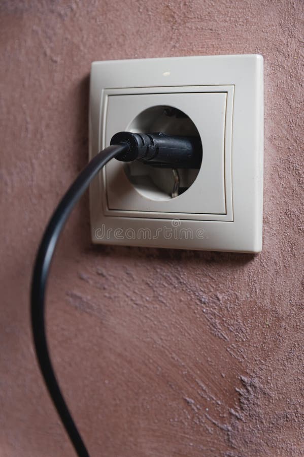 White Electrical Outlet on the Wall with a Black Wire Inserted. Close ...