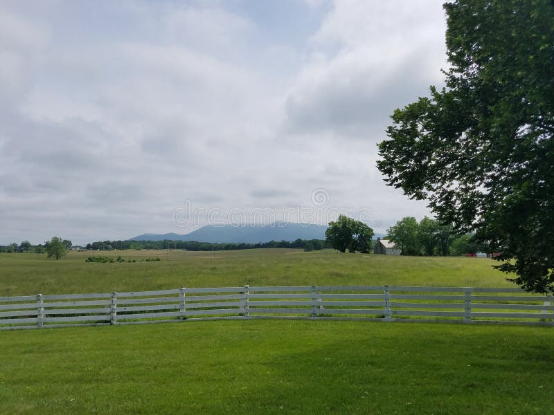 White Fence, Green Grass, and Mountains in the Distance Stock Image ...