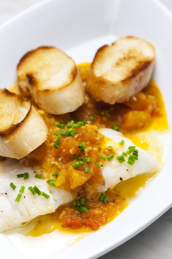 White Fish with Tomato Sauce and Roasted Baguette Slices Stock Image ...