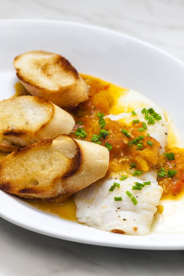 White Fish with Tomato Sauce and Roasted Baguette Slices Stock Image ...