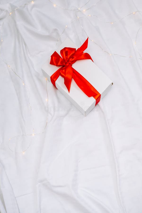 White Gift Box with Red Bow on White Sheet, Top View. Copyspace. Stock ...