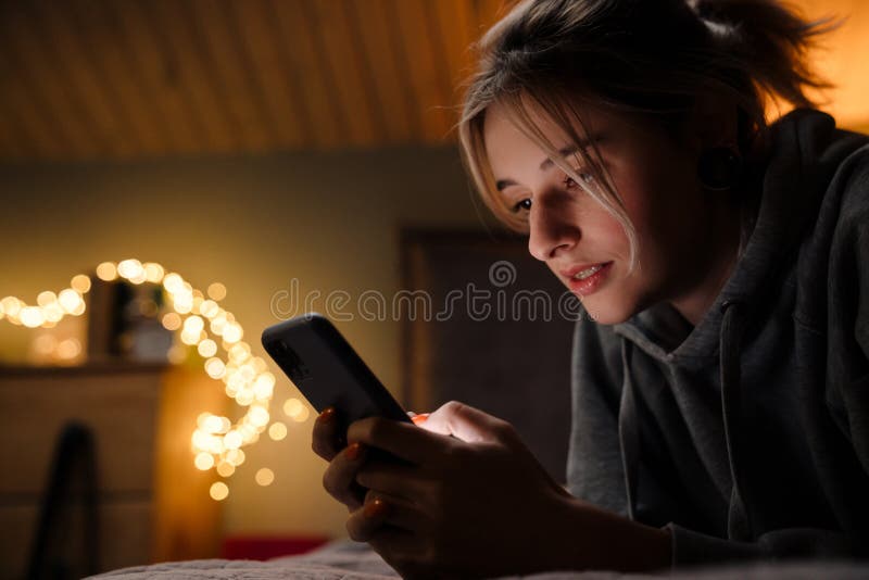 White Girl Using Mobile Phone while Resting on Bed Stock Image - Image ...