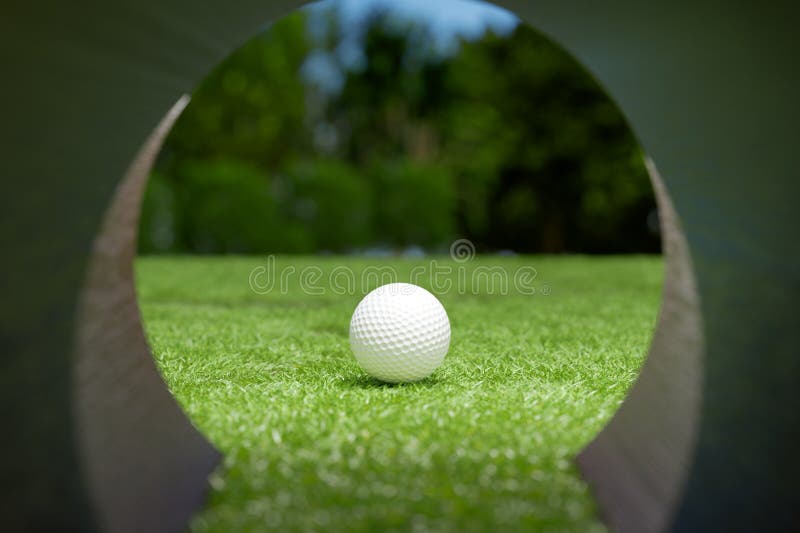 A White Golf Ball Sits on Green Grass, Framed by a Circular Opening ...
