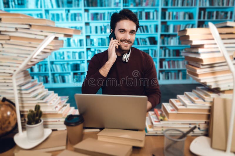 White Guy Surrounded by Books in Library. Student is Using Laptop and ...