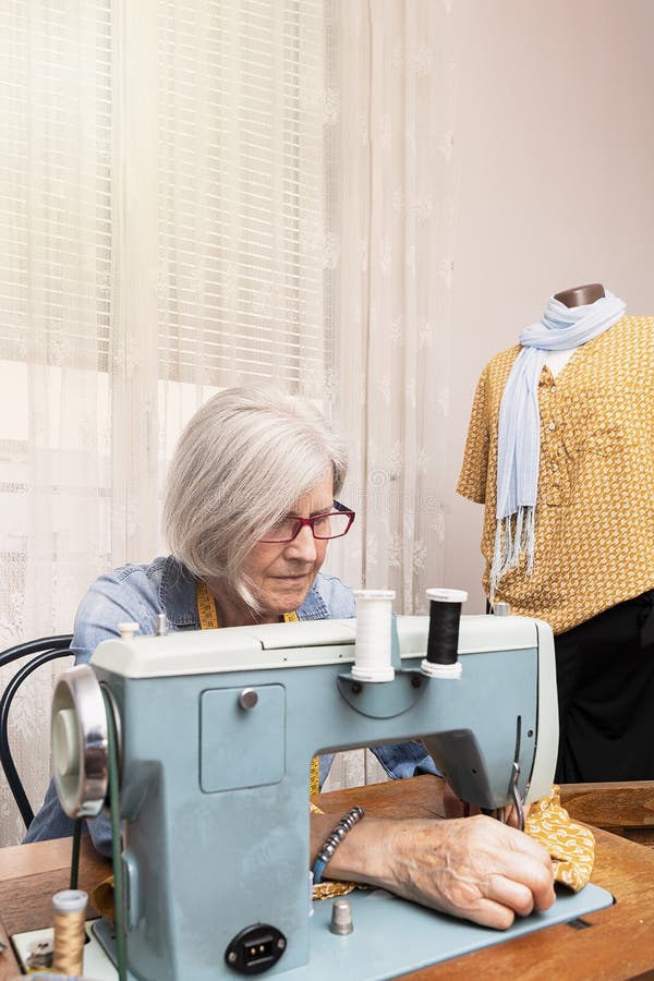 White-haired Older Woman Sewing in Front of an Old Sewing Machine in a ...
