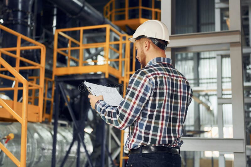 In White Hard Hat. Construction Worker in Uniform is in the Factory ...