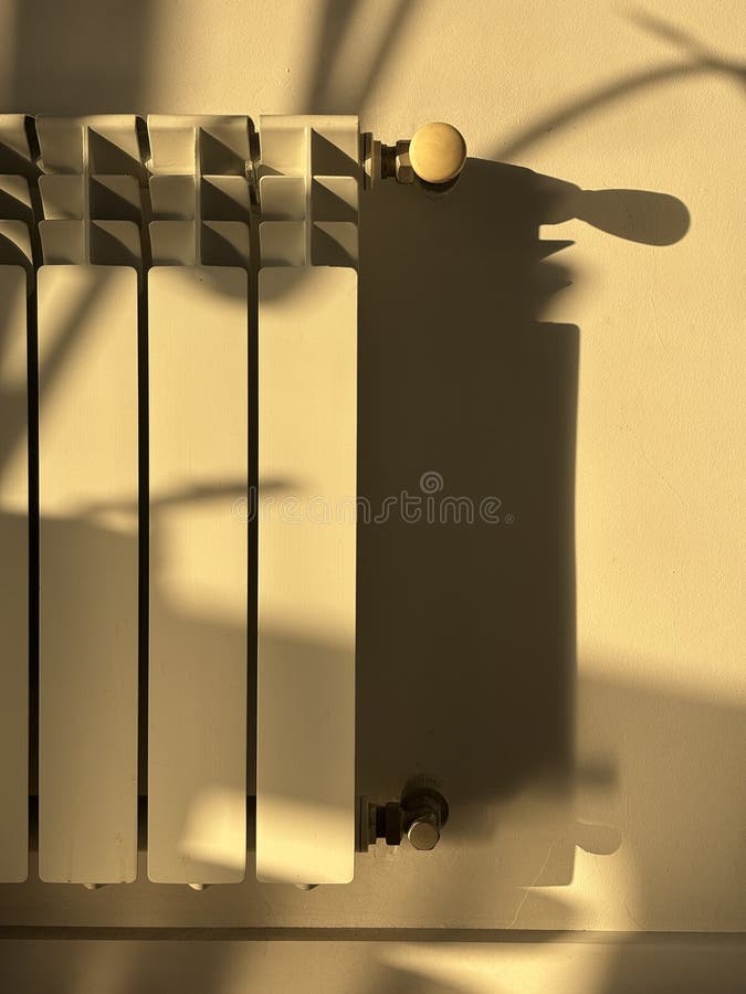 White Heating Radiator Mounted on a White Wall, Illuminated by Sunlight ...