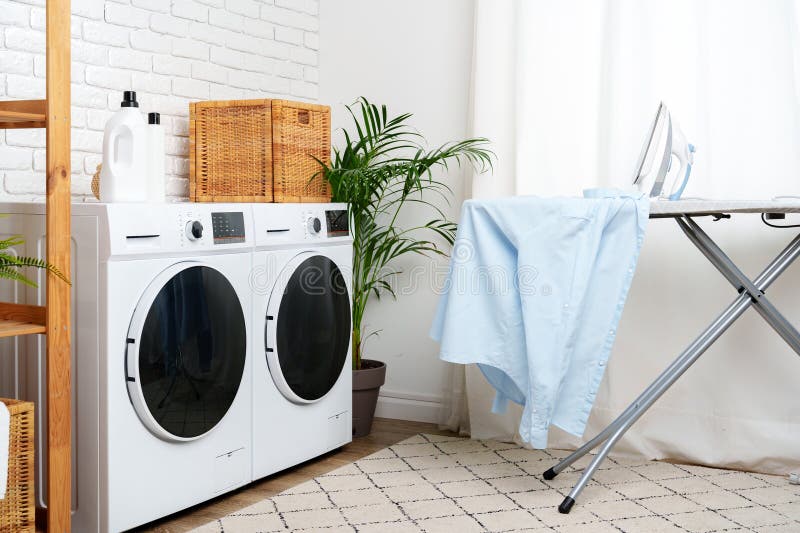 White Iron on Grey Ironing Board Next To Laundry Machines in White Room ...