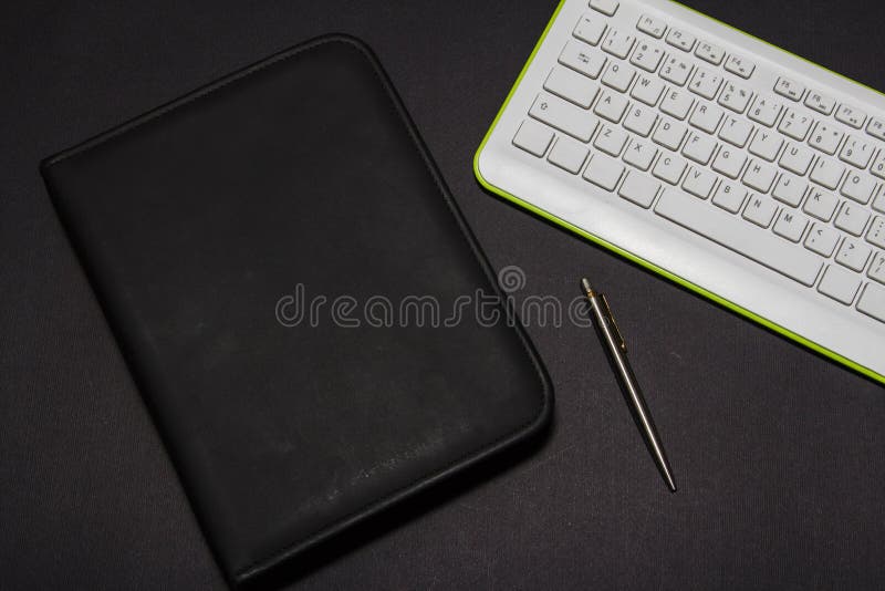 White Keyboard on a Black Background with Leather Folder and Pen. View ...
