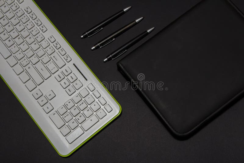 White Keyboard on a Black Background with Leather Folder and Pen. View ...