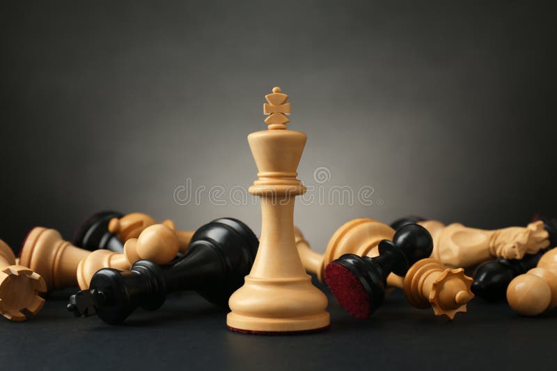 King among Fallen Chess Pieces on Black Table Against Dark Background ...