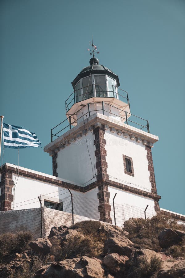 White Lighthouse on the Island with a Waving Greek Flag Stock Photo ...
