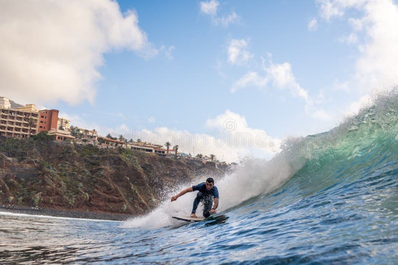 White Man Riding a Beach Wave with Buildings and Clouds in the ...