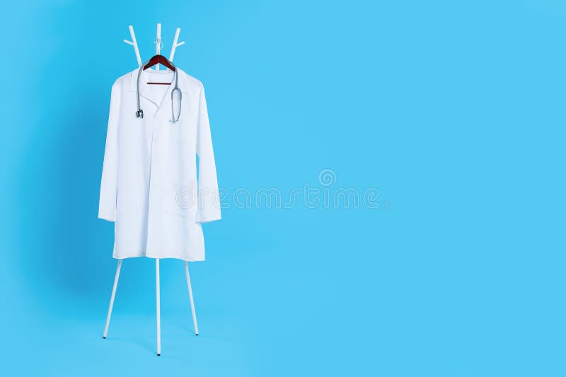 White Medical Uniform and Stethoscope Hanging on Rack Against Light ...