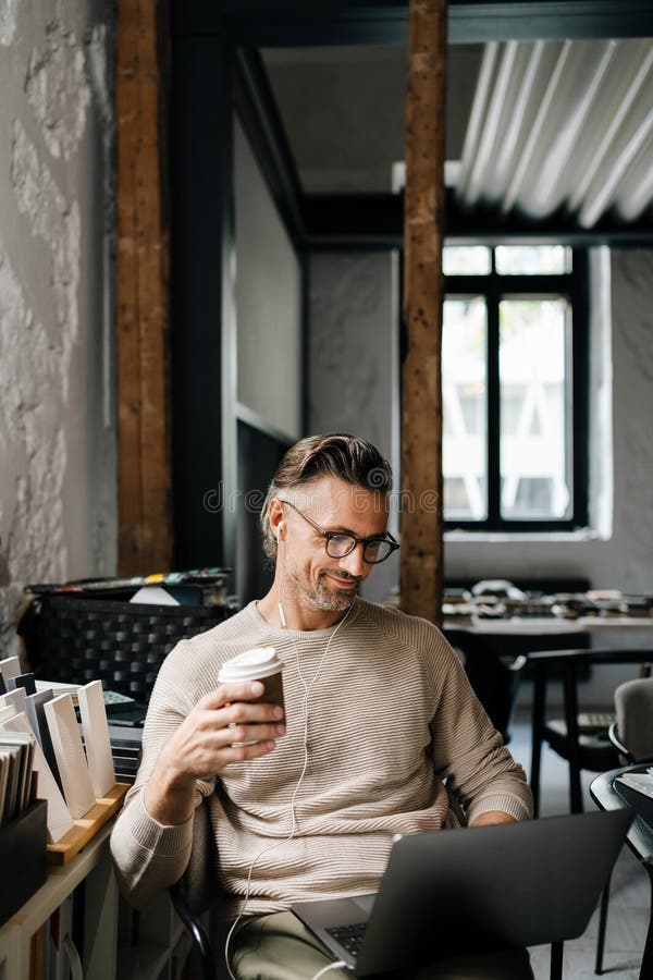 White Middle-aged Man Drinking Coffee while Using Laptop Computer in ...
