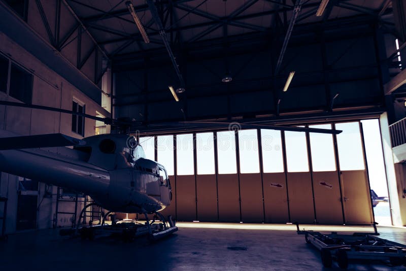 White Military Helicopter Parked Inside a Garage with a Closed Gate ...