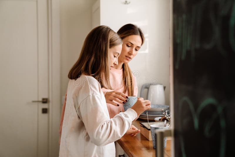 White Mother and Daughter Talking and Drinking Tea in Kitchen Stock ...
