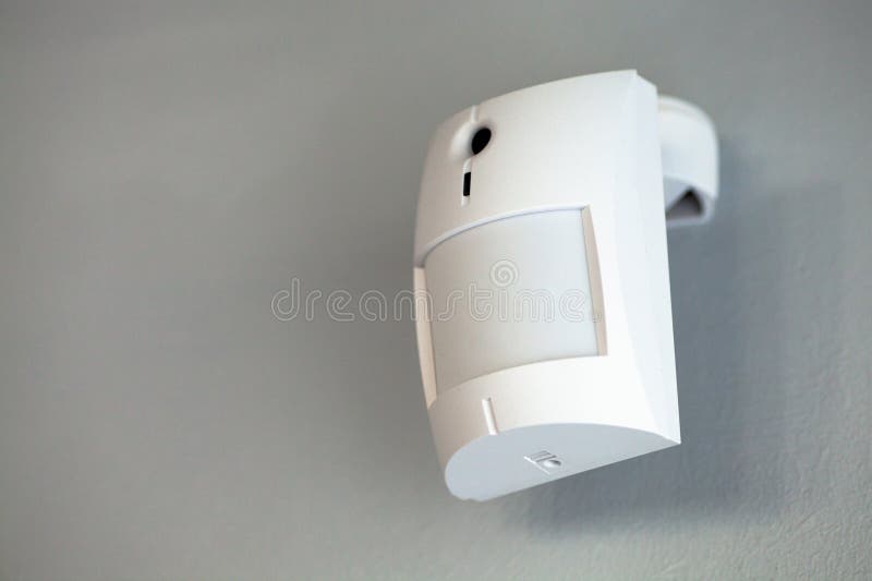A White Motion Sensor Camera on a Gray Wall, Providing Security and ...