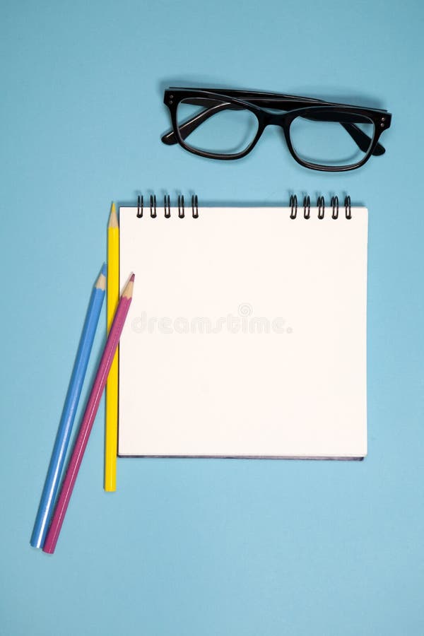 White Notebook on Springs, Glasses and Colored Pencils on a Blue ...