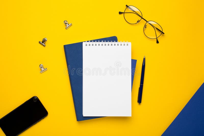 White Notepad with Blue Notebook and Pen on Yellow Background Stock ...
