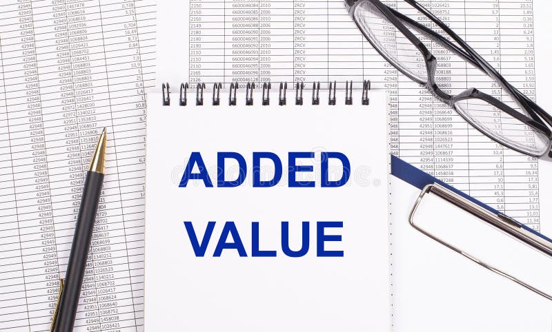 A White Notepad with the Text ADDED VALUE, a Pen, Reports and Glasses ...