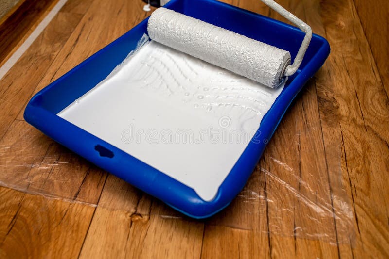 White Paint is Poured into a Blue Tray, a Roller in the Paint in the ...