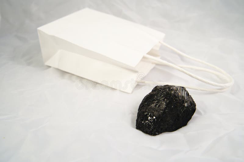 White Paper Bag and a Glittering Black Stone on a White Fabric Under ...