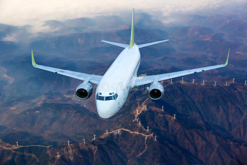 White Passenger Plane Flies Above the Mountain Landscape. Front View of ...