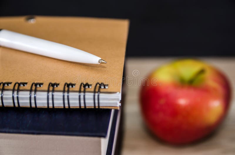 A White Pen on a Notebook and an Apple on a Table. Education Concept ...
