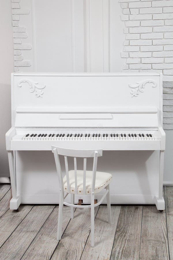 White Piano with White Stool in Front of a White Brick Wall Stock Photo ...