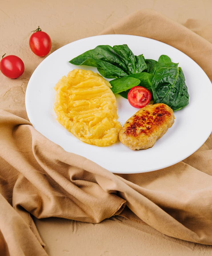 White Plate Showing Chicken Kiev with Mashed Potatoes and Spinach Being ...