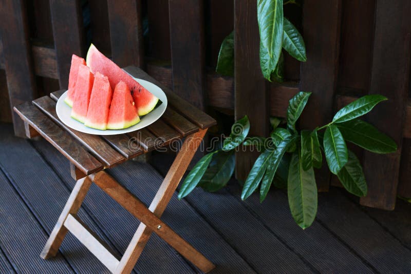 White Plate with Sliced Watermelon on Wooden Stool Outdoors. Space for ...