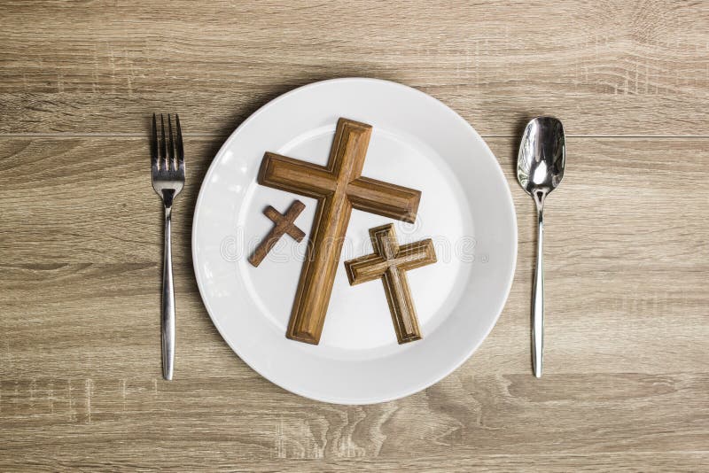 A White Plate with a Wooden Cross Over the Wooden Table. Stock Photo ...