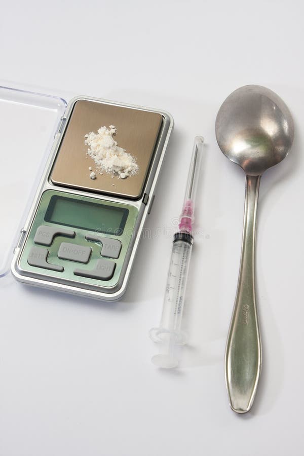 White Powder and Syringe with Needle and Metal Spoon on a Digital Scale ...