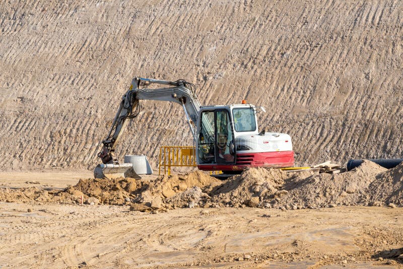 White and Red Small Excavator Moving Earth in the Middle of a Large ...