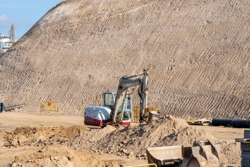 White and Red Small Excavator Moving Earth and Sand in the Middle of a ...