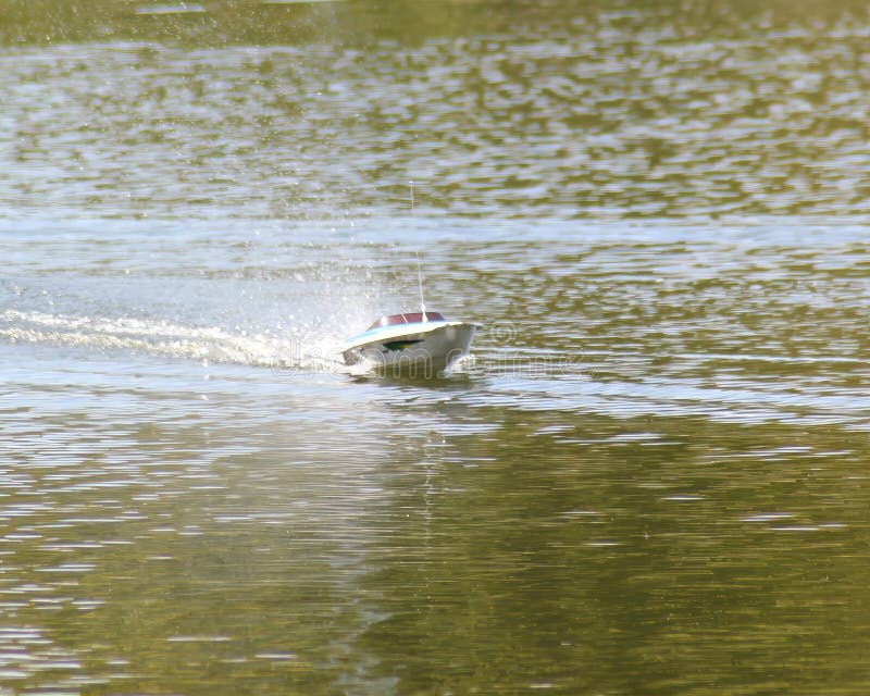 White Remote Control Boat Racing Across Calm Water with Wake, Spray ...