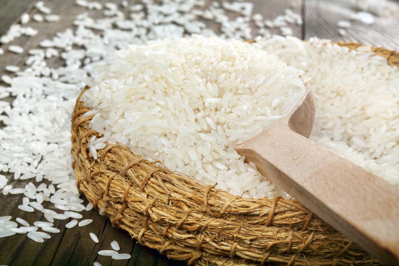 White Rice in Wicker Bowl with Wooden Spoon on Wooden Table Stock Photo ...