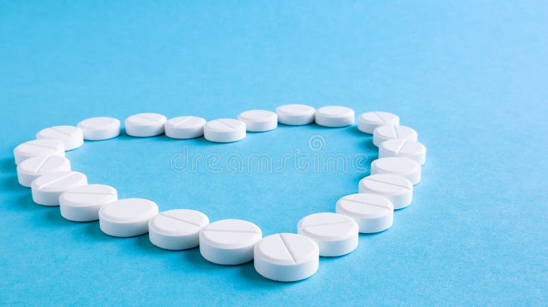White Round Pills Laid Out In The Shape Of A Heart On A Blue Background