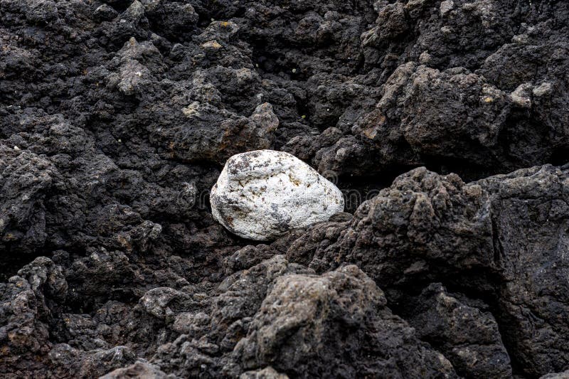 White Round Stone in the Center of Dark Colored Rock Formations with ...